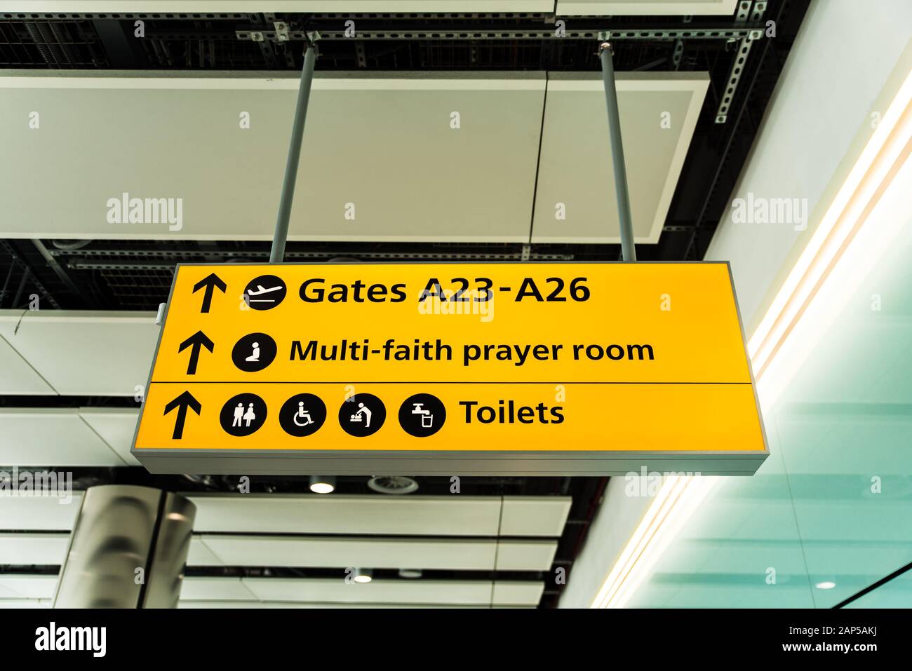 Yellow illuminated sign board pointing the direction to gates, toilets ...