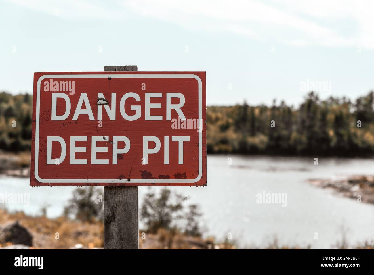 Deep pit danger sign. Red warning signage in field for workplace safety ...