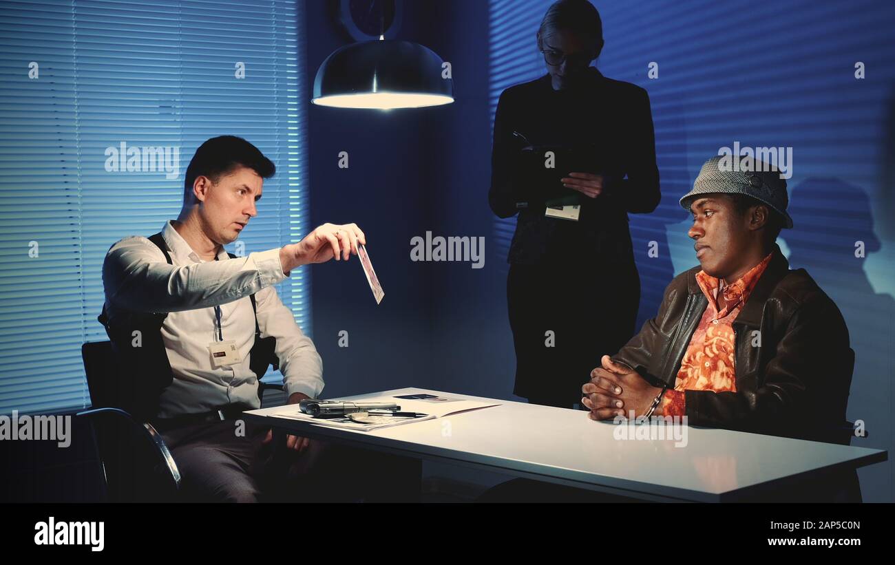 Medium shot of Detective showing picture of suspected robber's ...