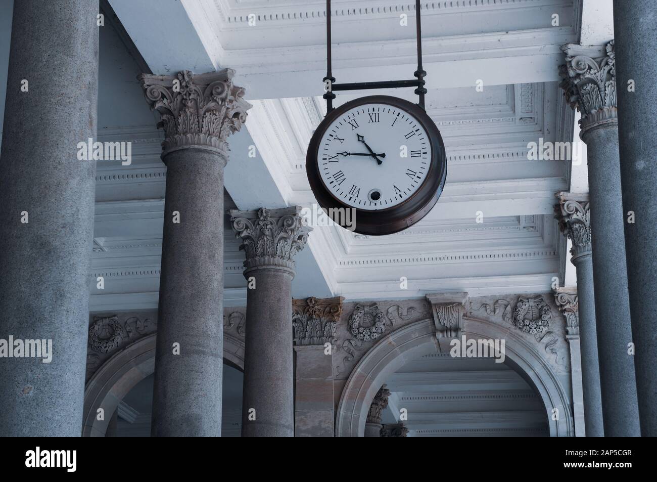 Antique clock hanging from ceiling with stone columns Stock Photo - Alamy