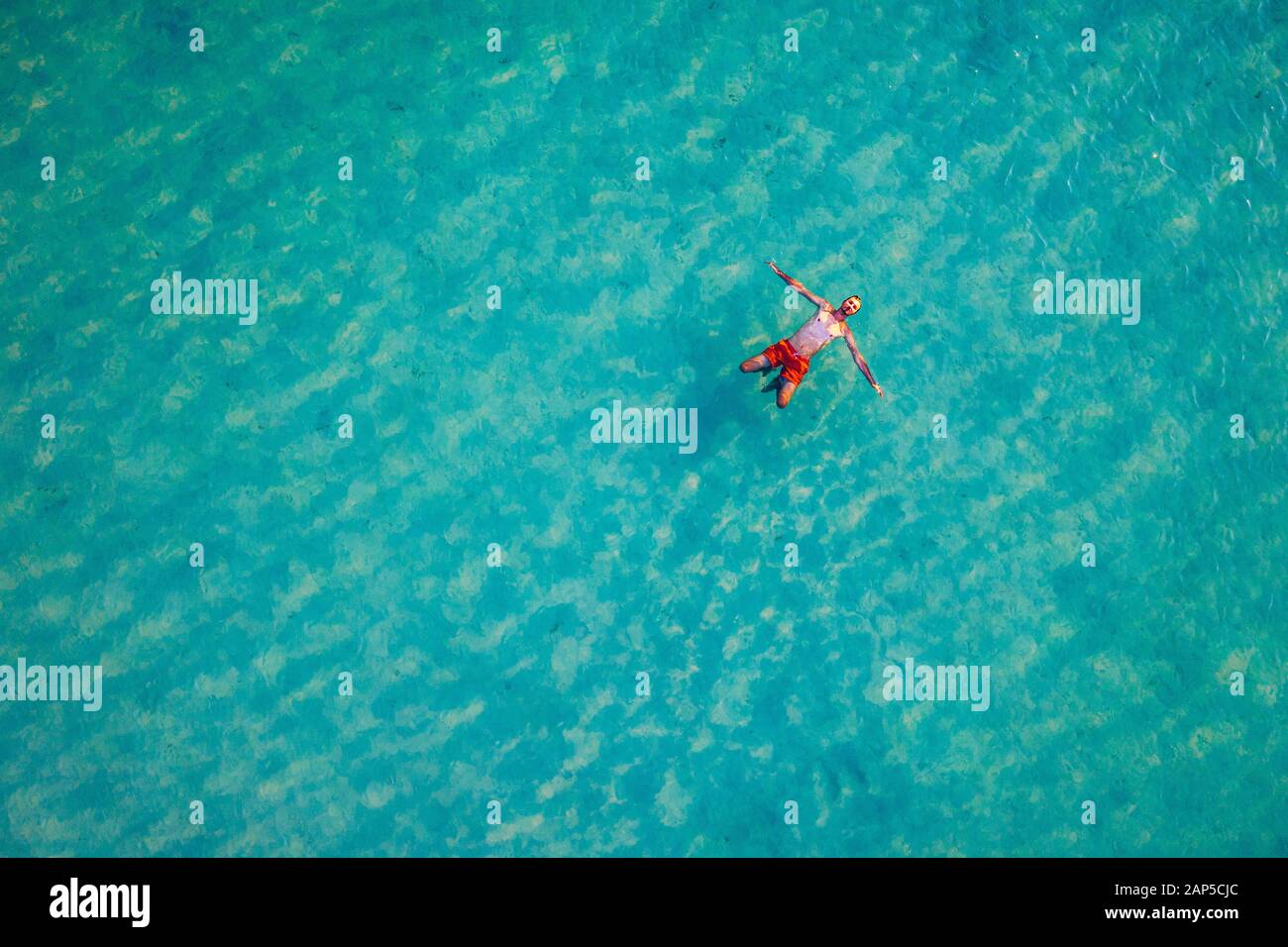 Drone view of a man floating in tropical sea water. Aerial view of ...