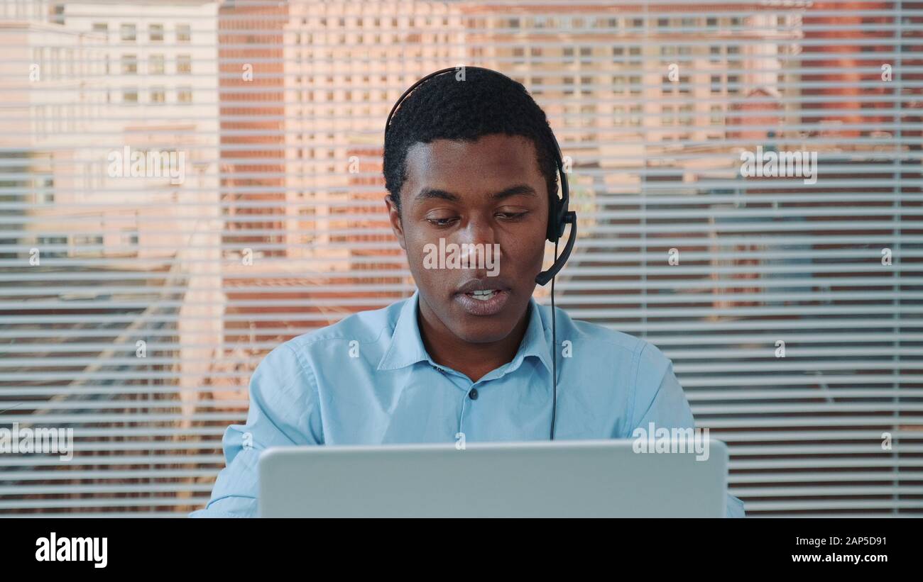 Black man in headset speaking with somebody and working on the computer ...