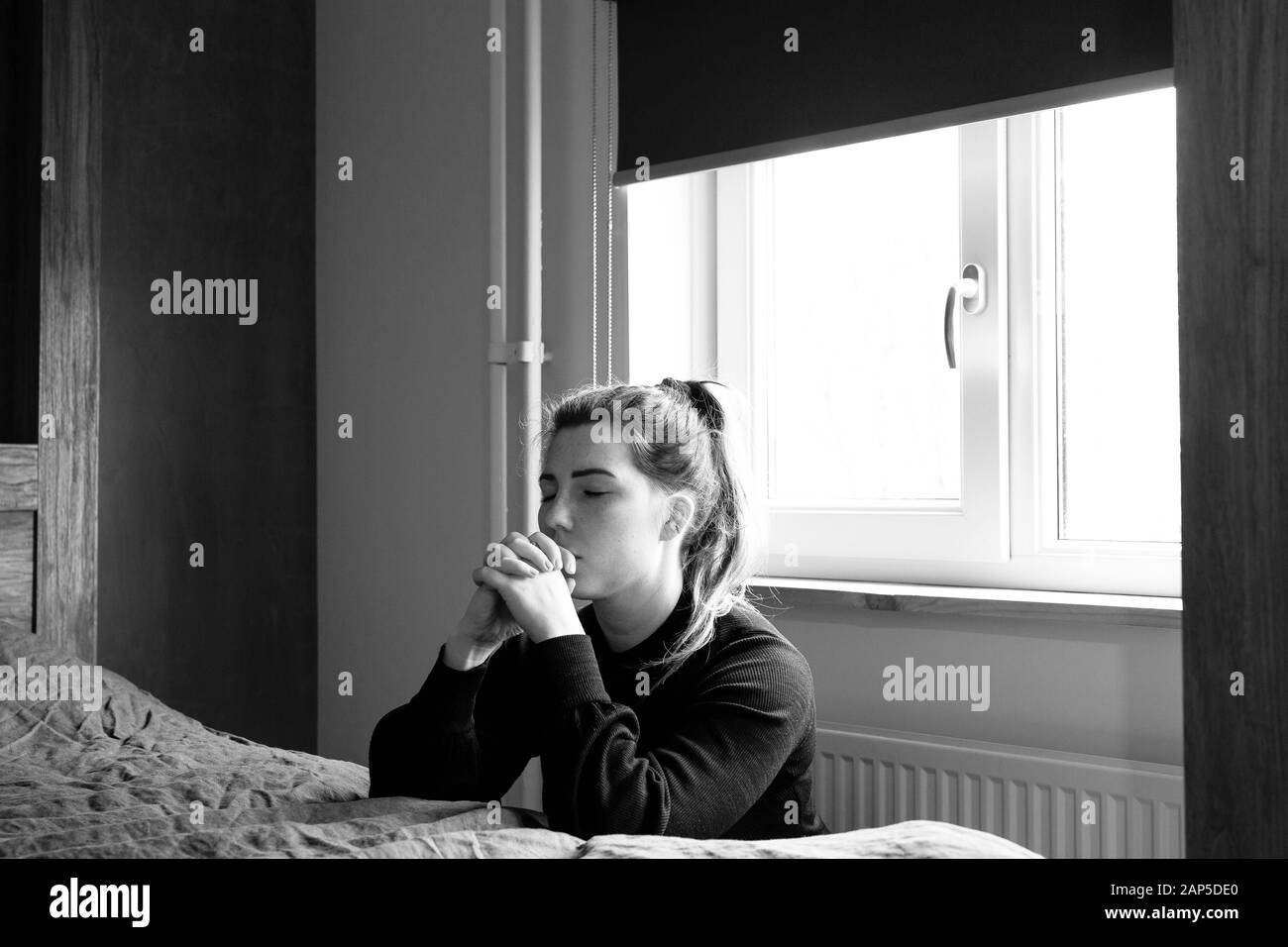 Religious Praying Woman is praying at her bed in the bedroom before ...