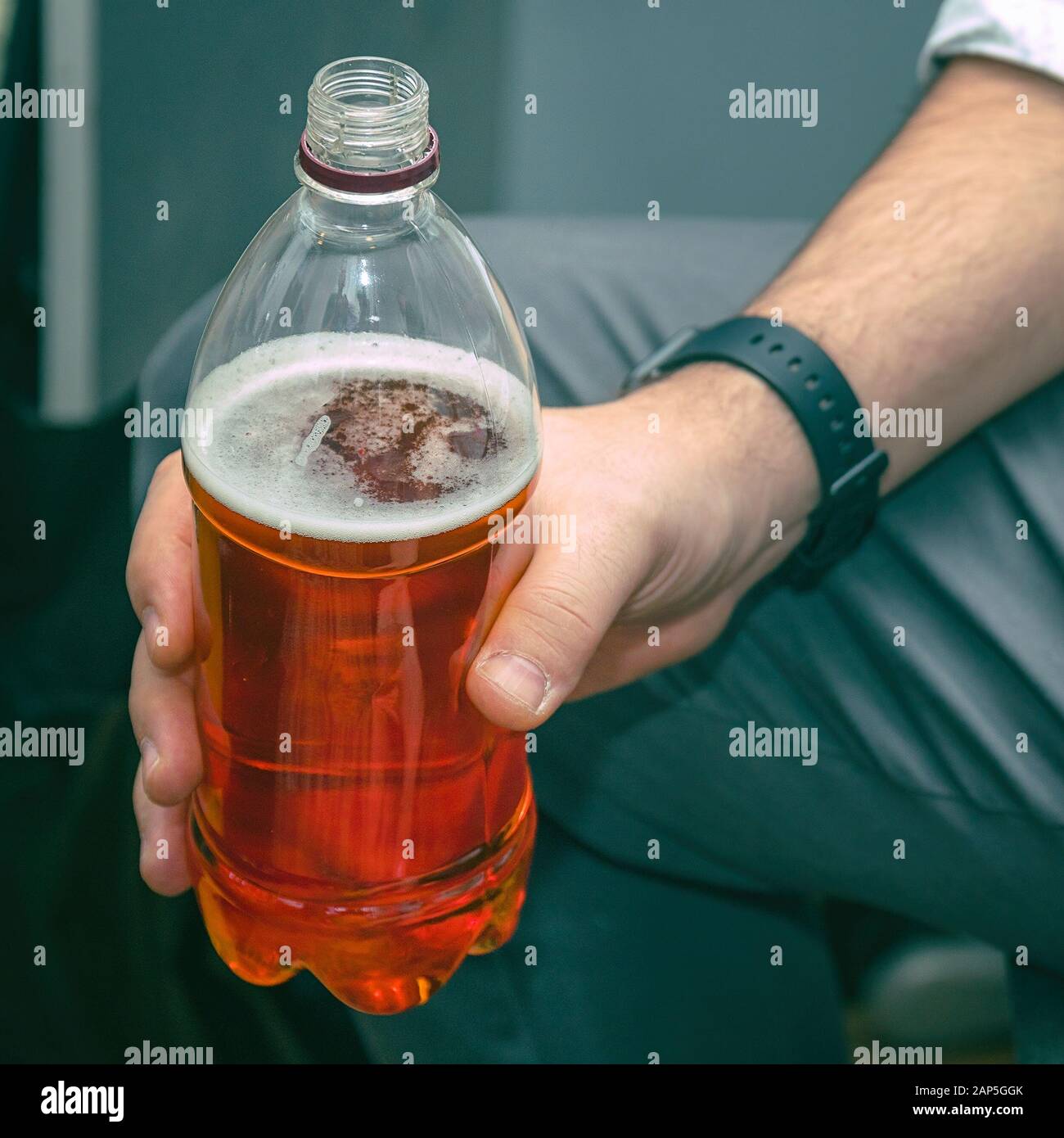 A man holds in his hand a plastic bottle with beer. Drink in a plastic ...