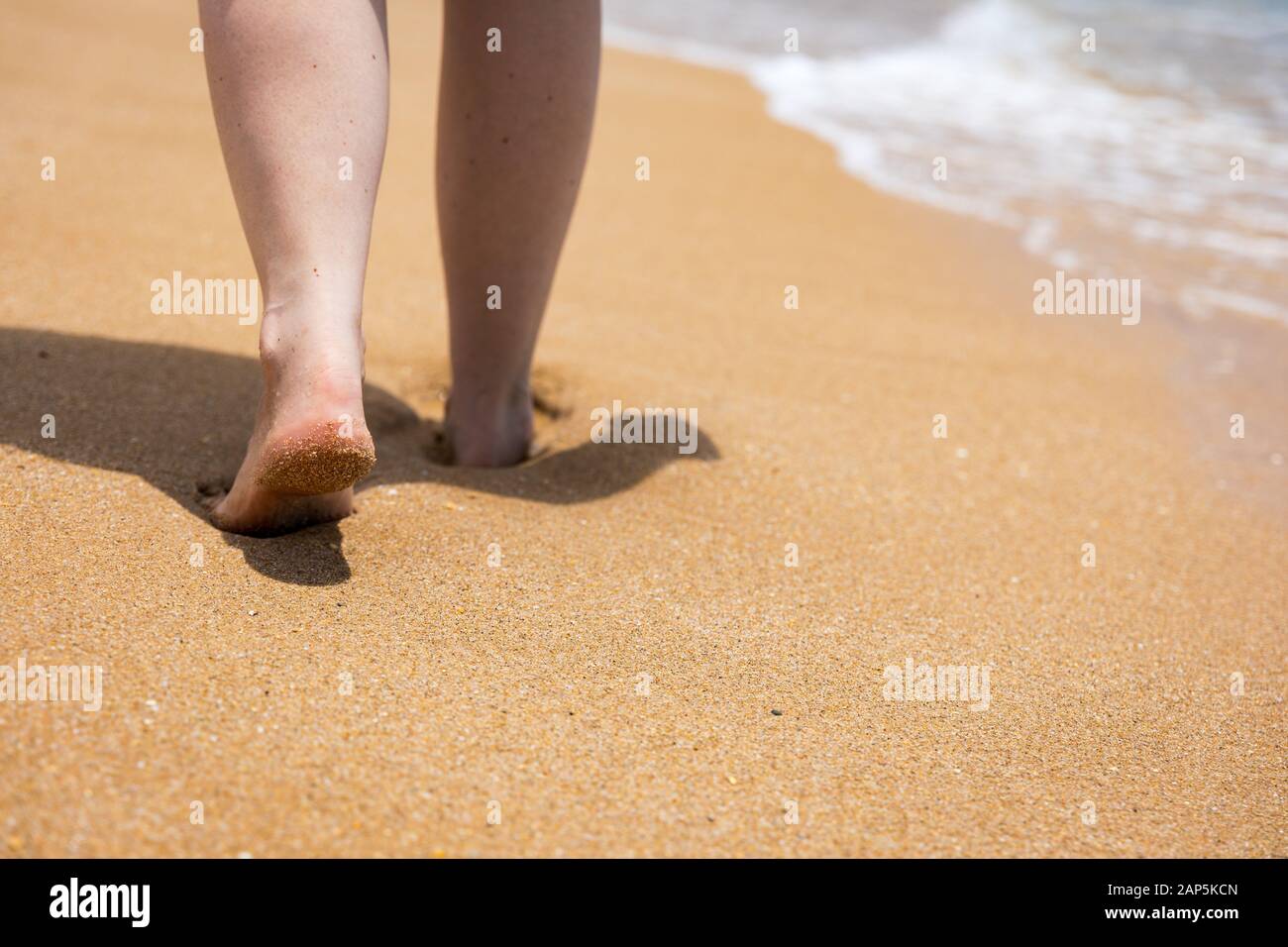 Woman walking barefoot on a beach. Close up leg of young woman walking ...