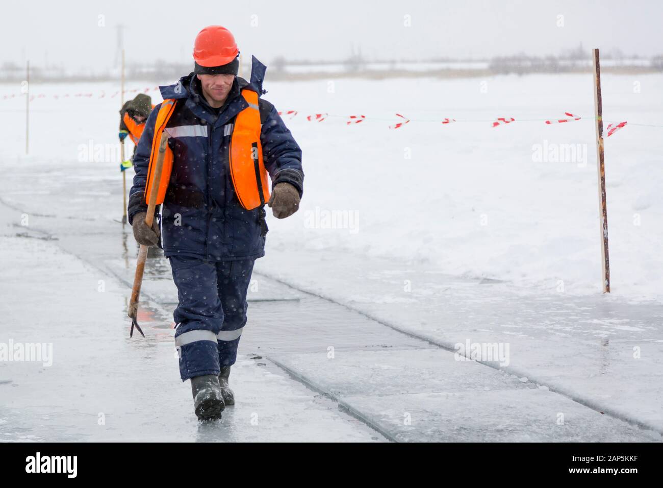Workers rafting ice blocks along a channel cut out by a frozen lake ...
