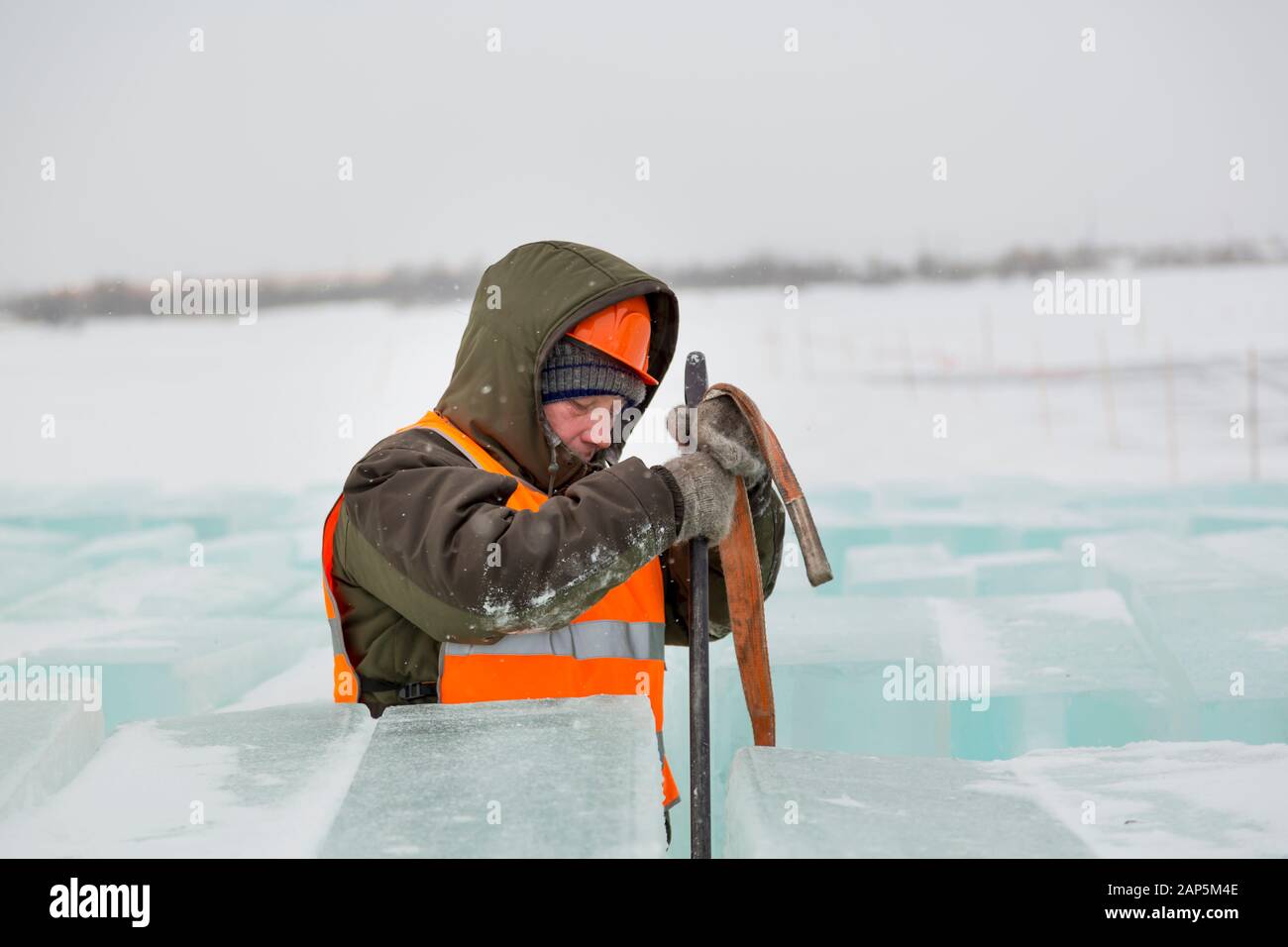 Slinger in orange helmet on shipment of ice blocks Stock Photo - Alamy