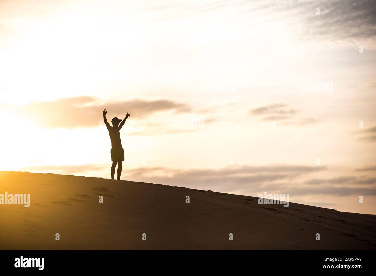 Young man raising his arms high in a victory or freedom gesture ...