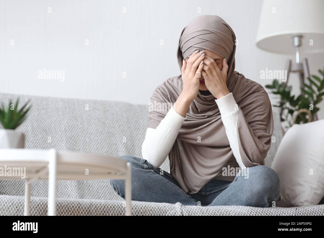 Crying muslim woman in hijab sitting on sofa at home Stock Photo - Alamy