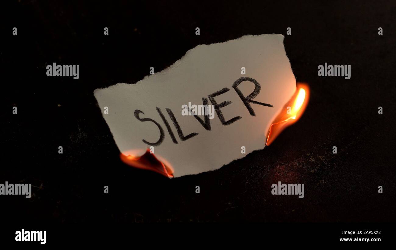 Silver word written on white paper burns. Fire with smoke and ashes on ...