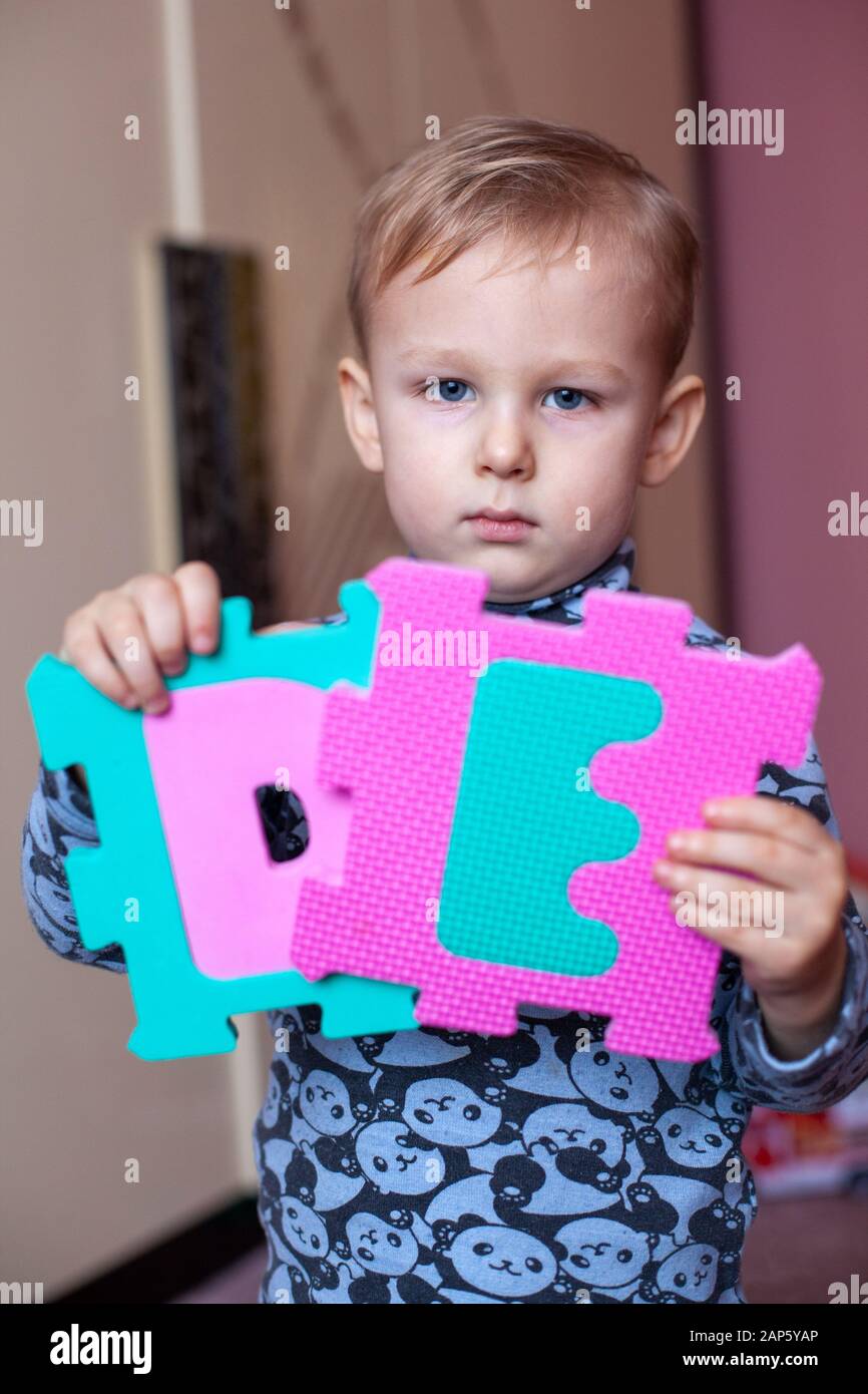 Little boy collects the puzzle sitting on floor. Big ABC squishy foam ...