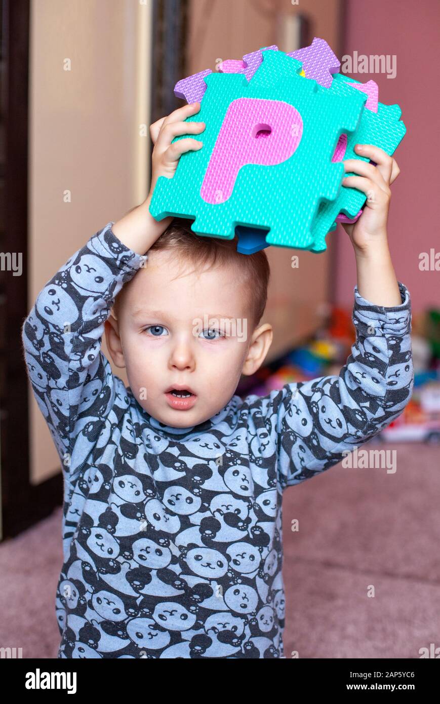 Little boy collects the puzzle sitting on floor. Big ABC squishy foam ...