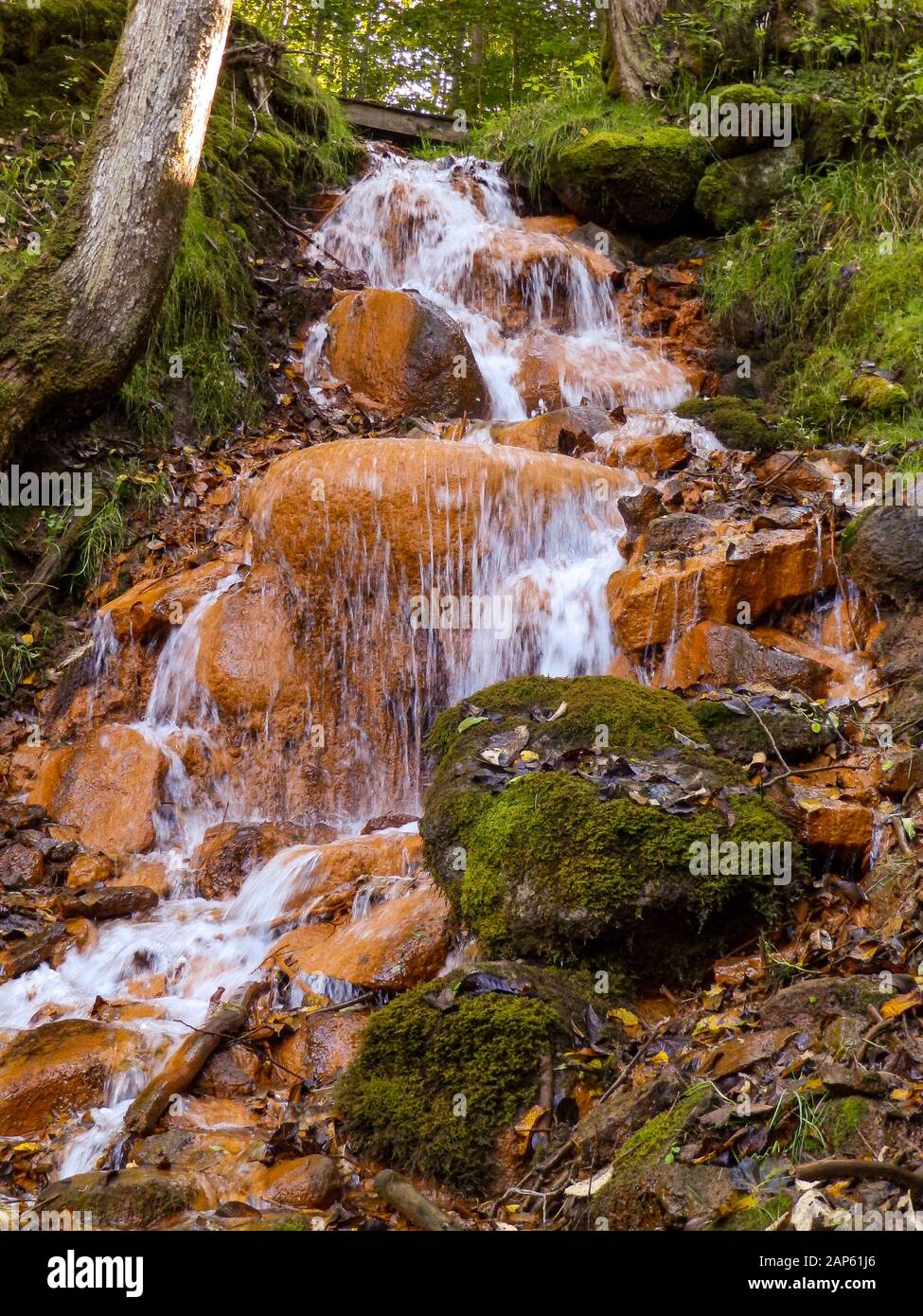 wild landscape with a small waterfall, running water in orange tones ...