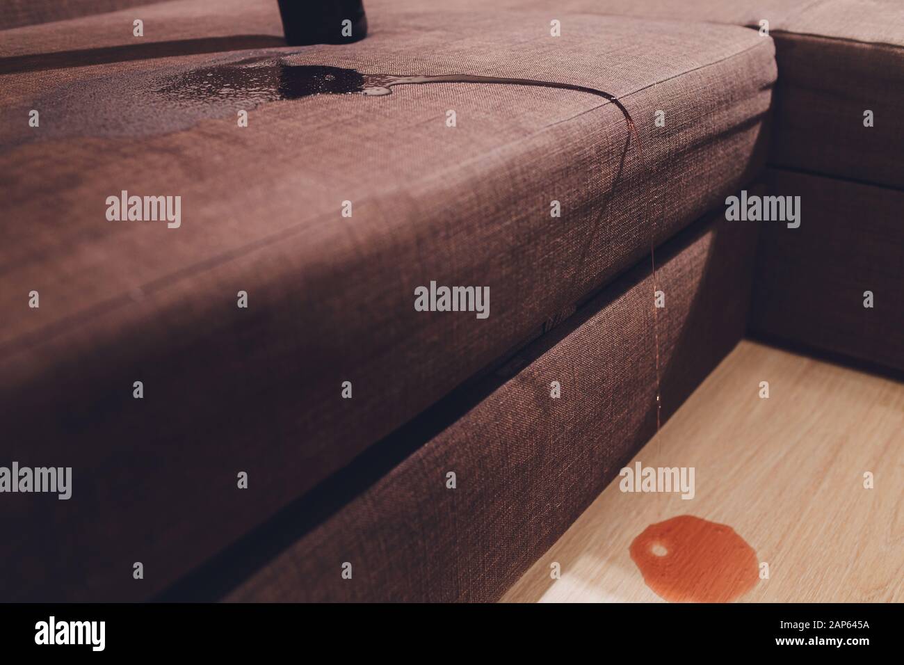 Red wine spilled on a brown couch sofa Stock Photo - Alamy