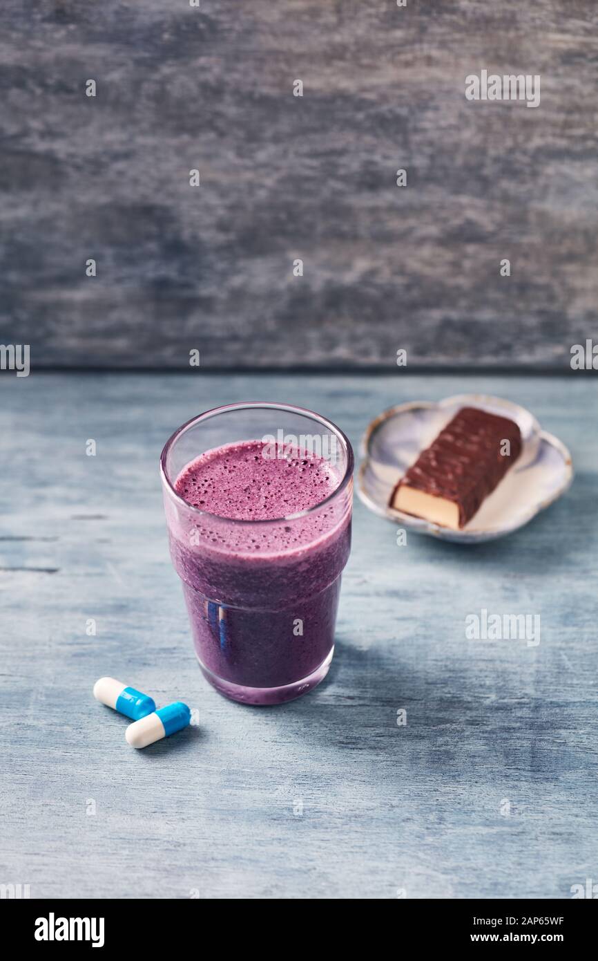 Glass of Protein Shake with milk and blueberries, Creatine capsules and ...