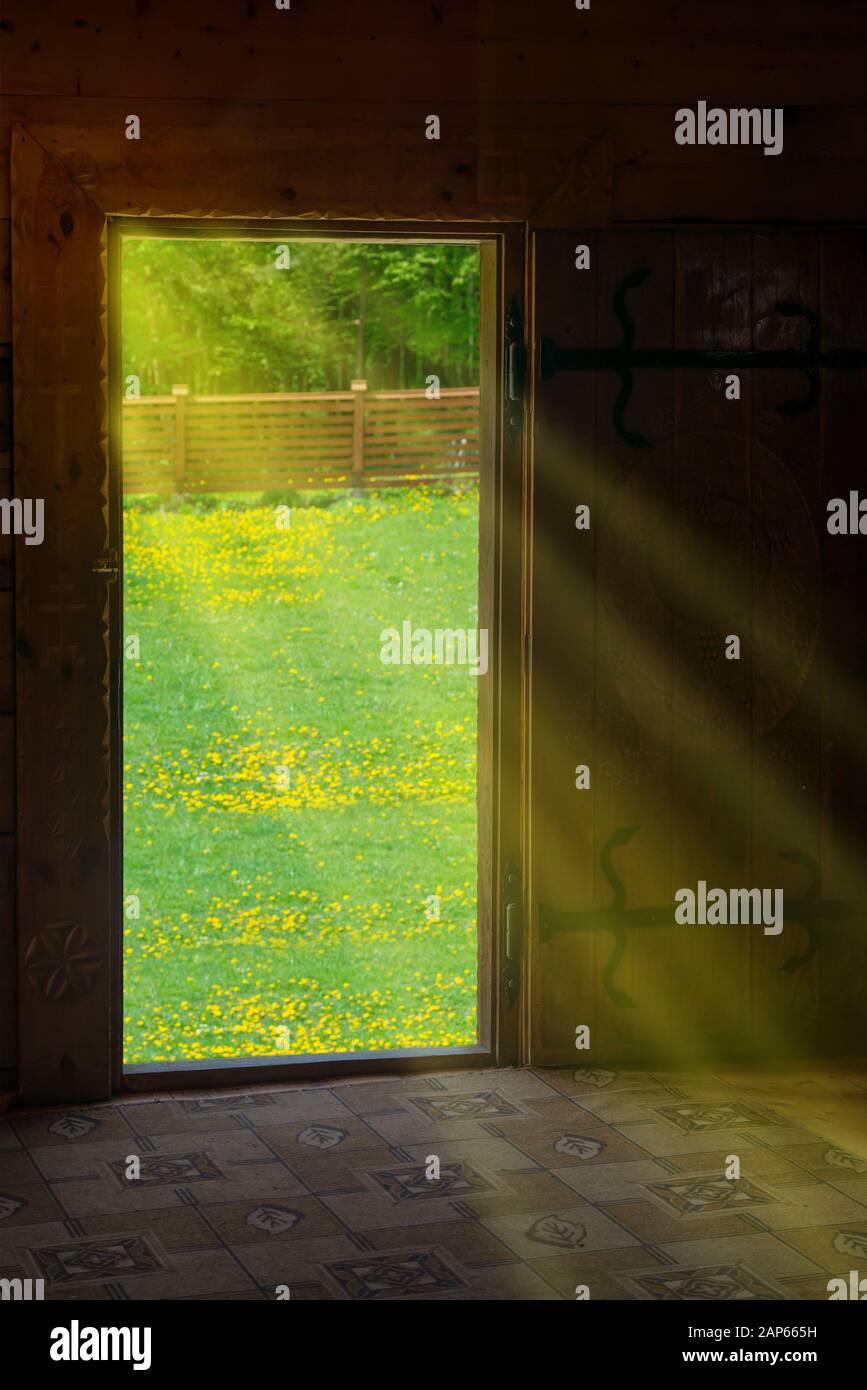 Sun light shining through wooden door from new world with green meadow ...
