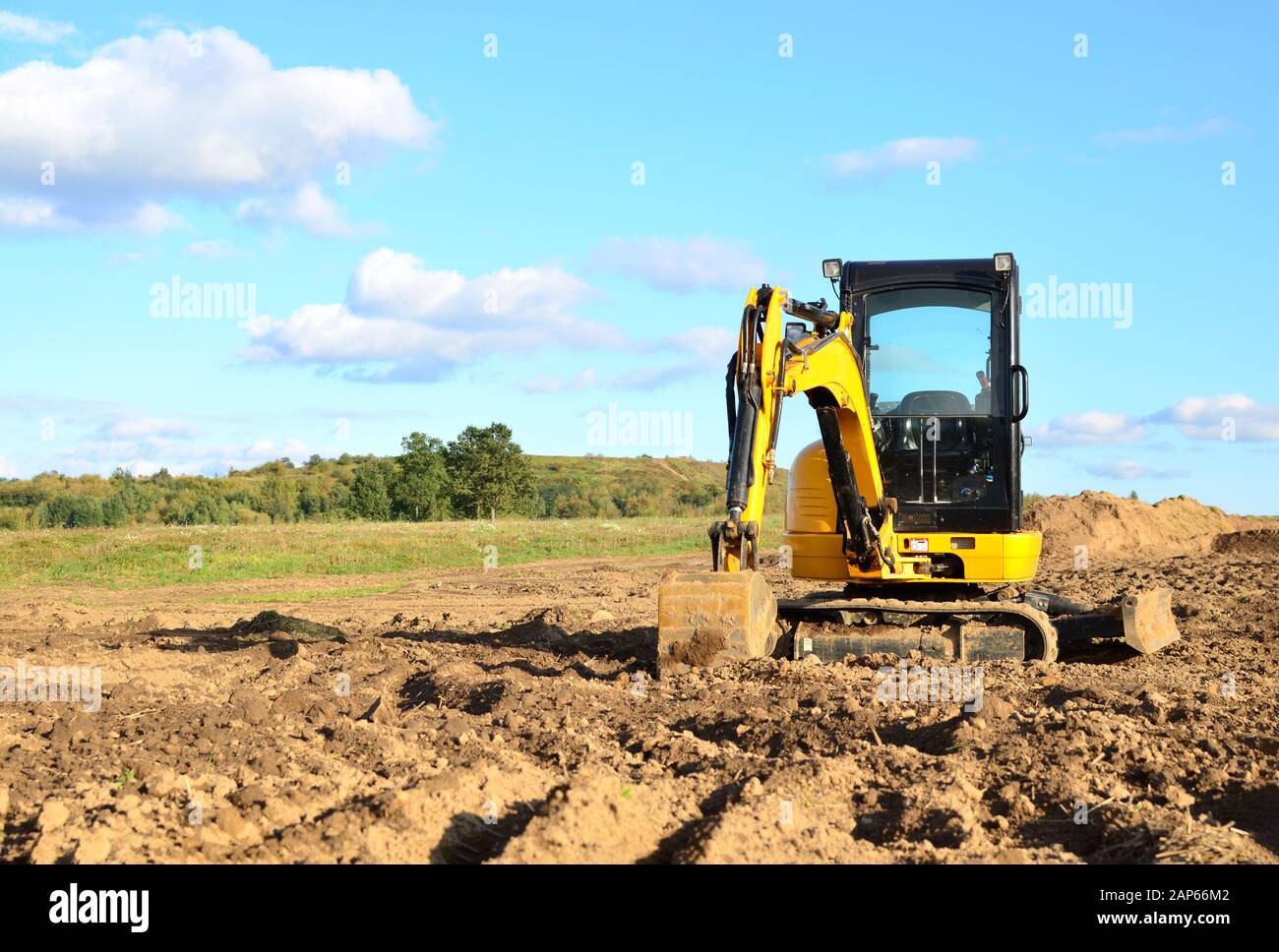 Mini excavator digging earth in a field or forest. Laying underground ...