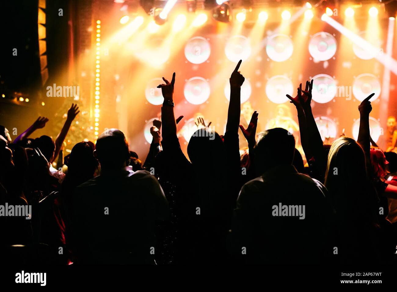 Crowd at a music concert, audience raising hands up in front of bright ...