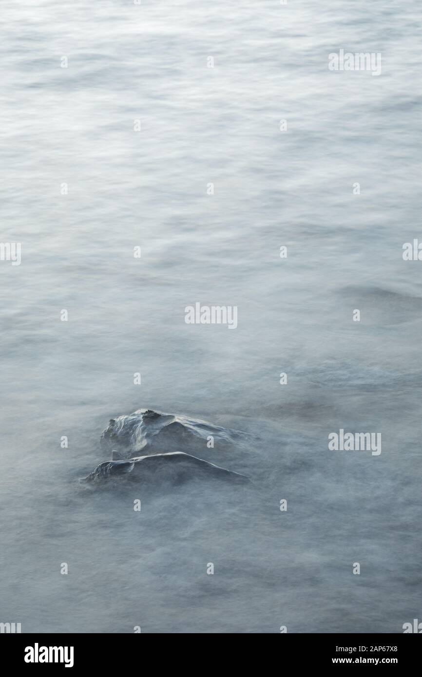 Abstract long exposure of waves and rocks in lake shore at dawn Stock ...