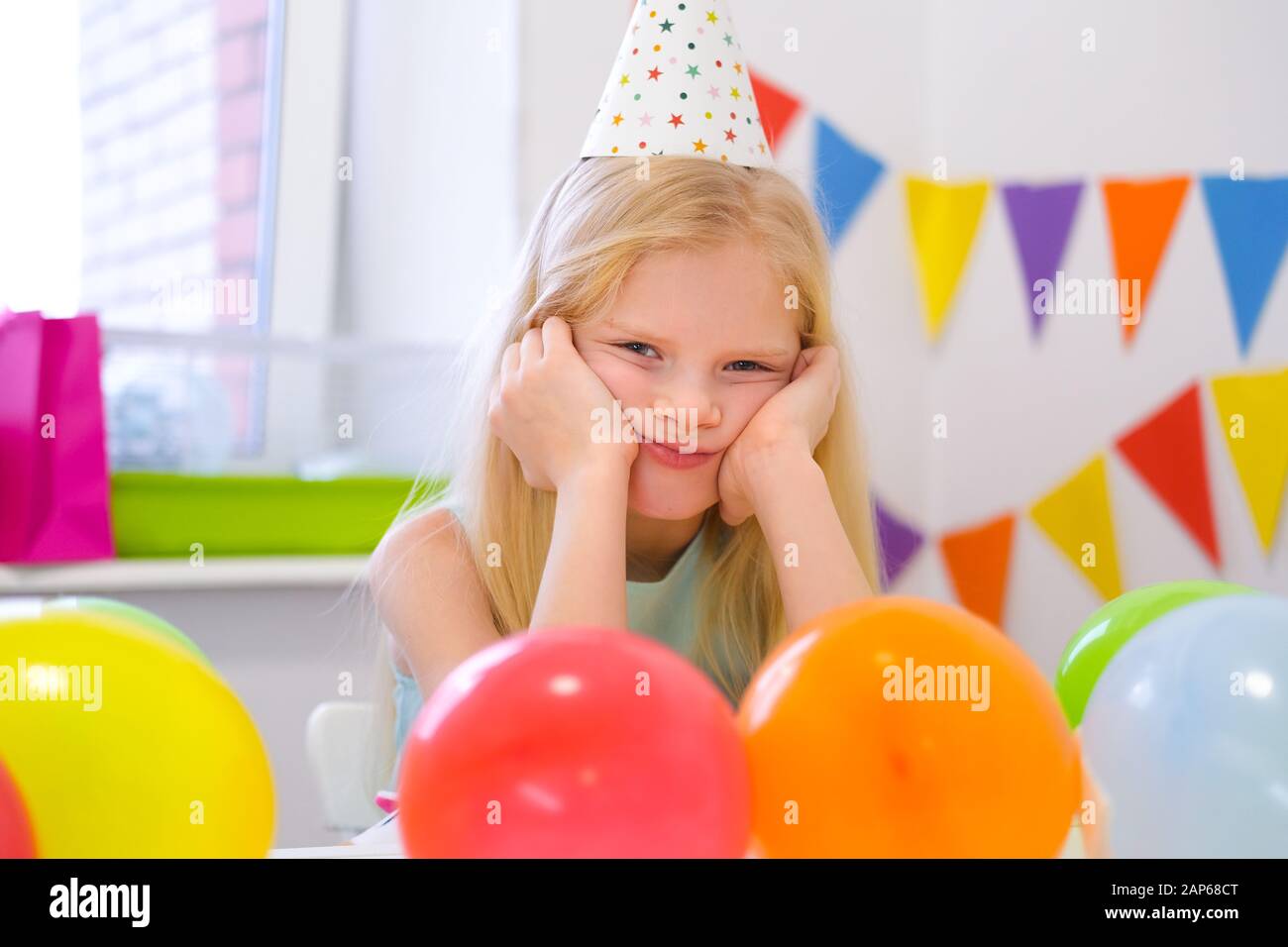 Unhappy blonde caucasian girl with boring face near birthday rainbow ...