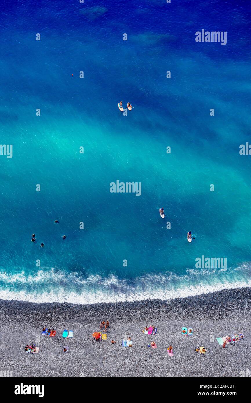 Tropical beach with colorful beach towls, people, divers and surfers ...