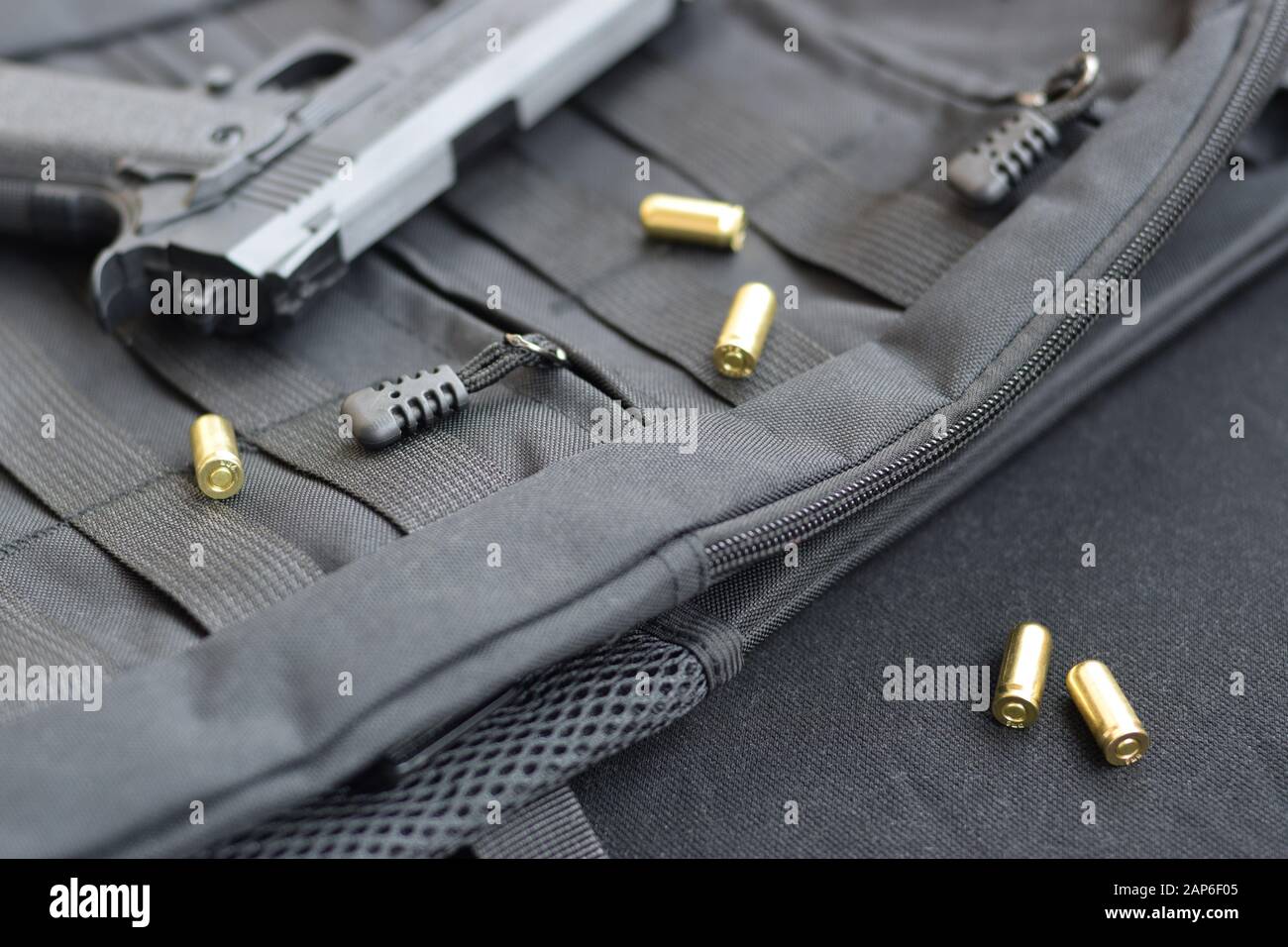 9mm bullets and pistol lie on a black tactical backpack. A set of ...