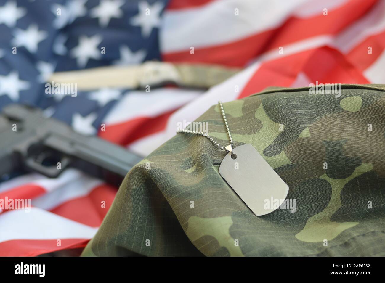 Army Dog tag token with 9mm bullets and pistol lie on folded United ...