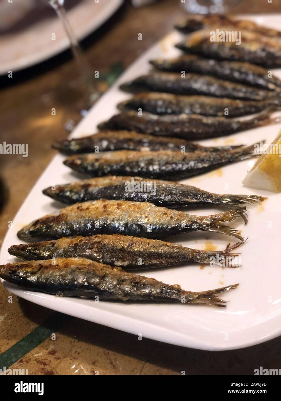 Plate with deep fried sardines and lemon Stock Photo - Alamy