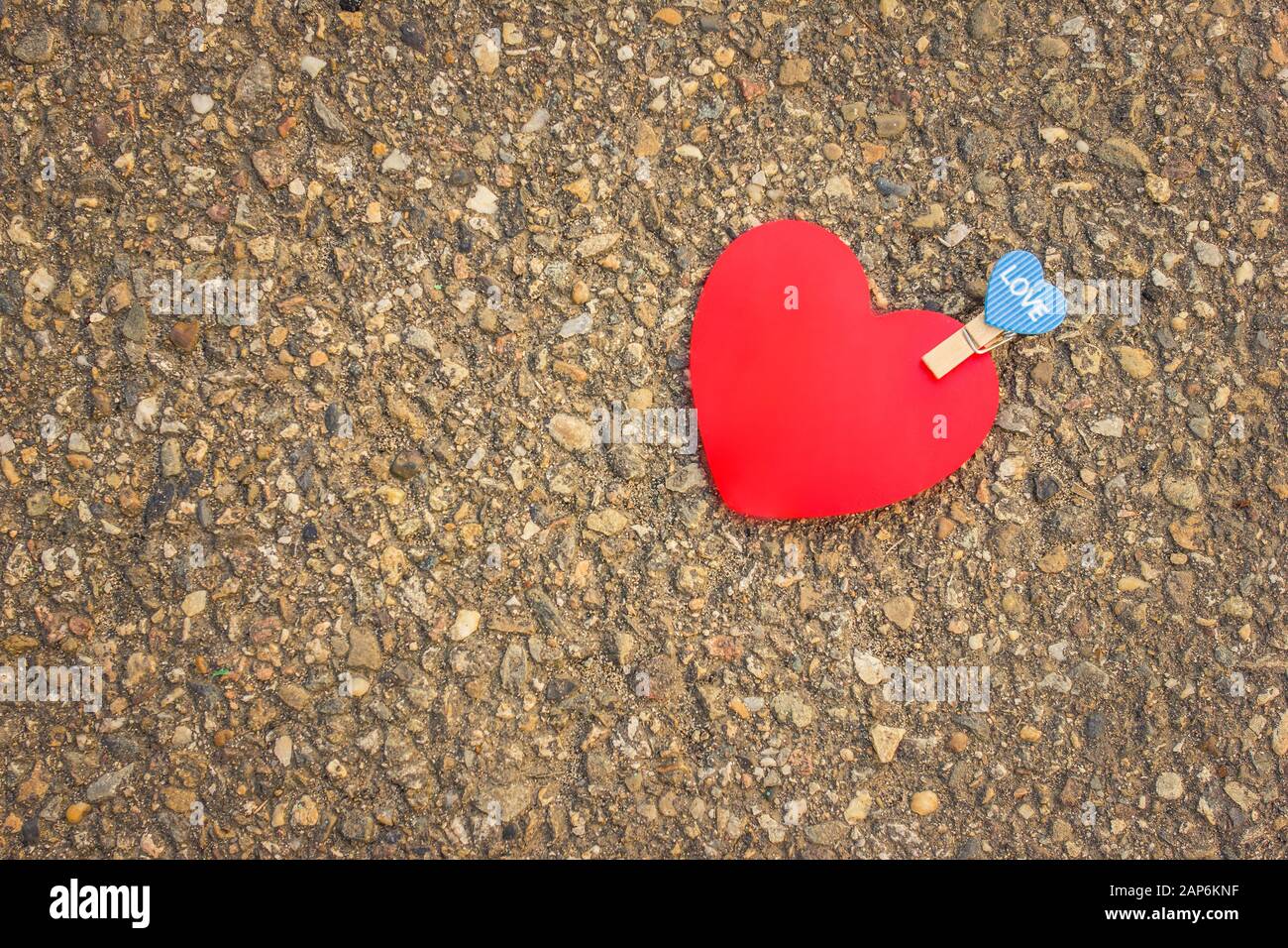 red heart lies on the pavement. a small blue heart attached to a big ...
