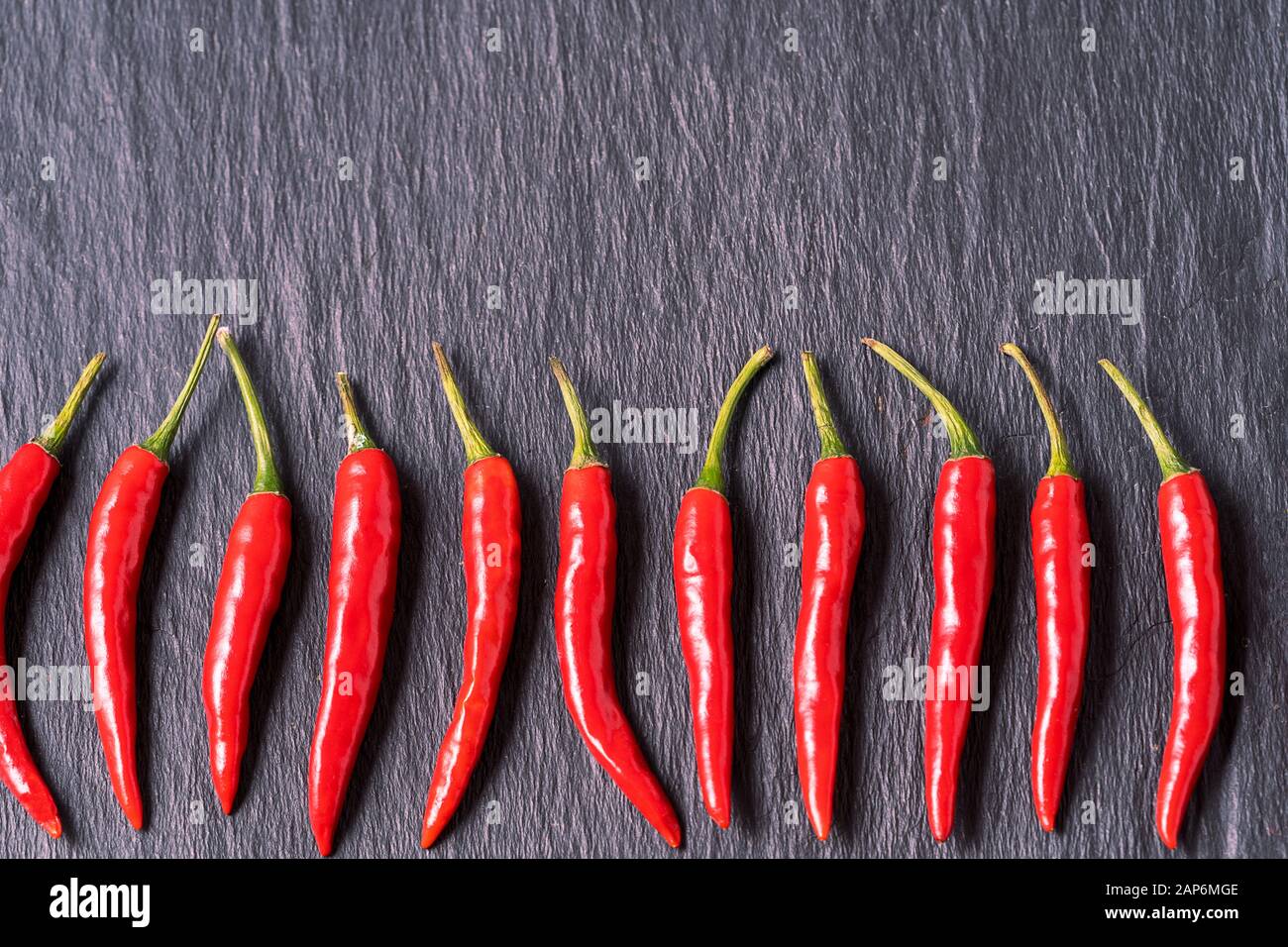 Flat lay horizontal row of red fresh spicy chili peppers pattern on ...