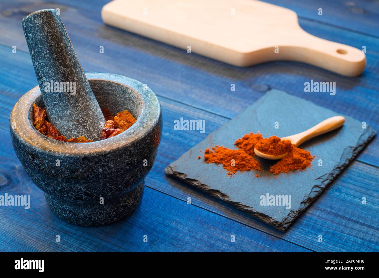 chilli peperoncini peppers in stone granite mortar on blue wooden desk ...