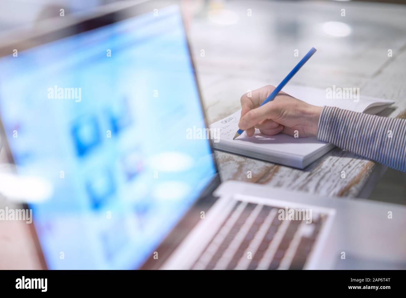 Closeup of laptop close to hand woman writing working with a pen on a ...