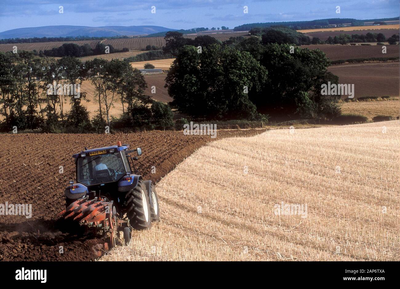 Farmer ploughing in a field of stubble with a 4 furrow reversible ...