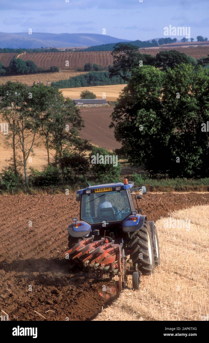 Farmer ploughing in a field of stubble with a 4 furrow reversible ...