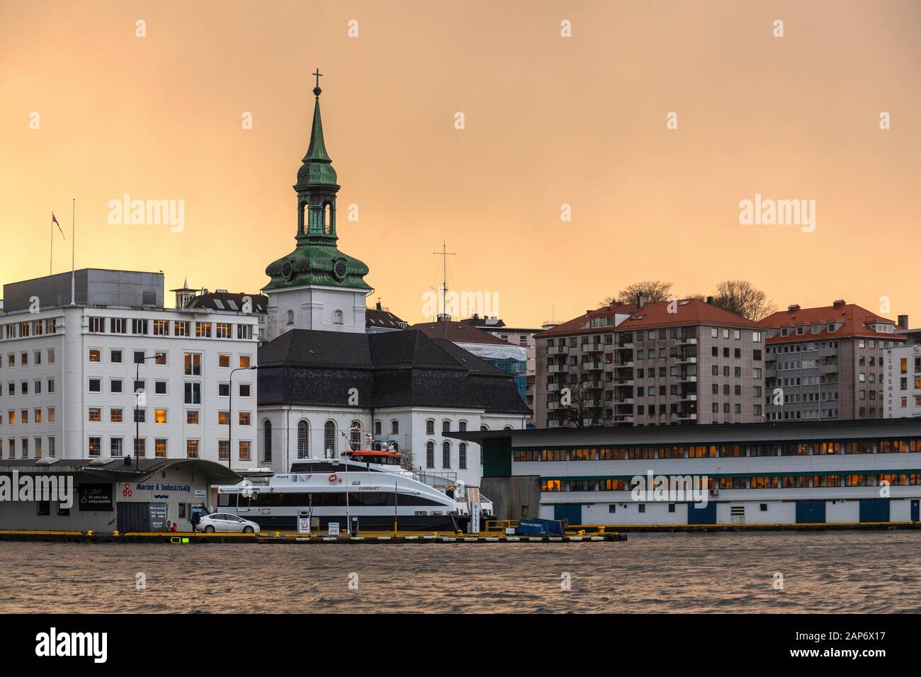 Port of Bergen, Norway. Old church Nykirken backlit with orange color ...