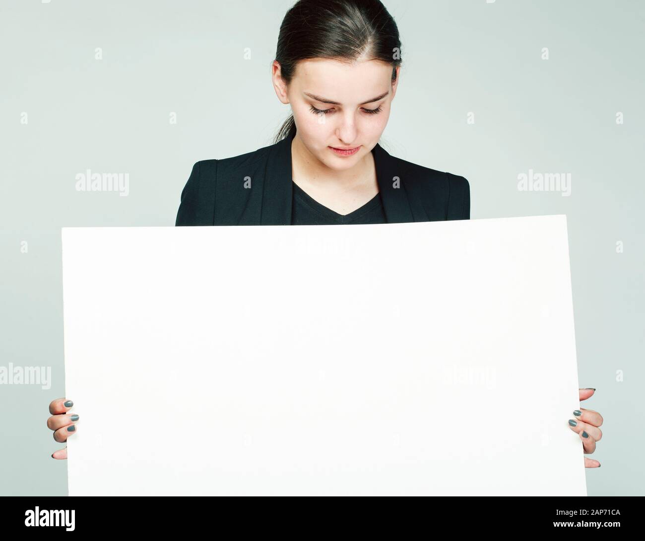 young pretty brunette girl with placard on white background wearing ...