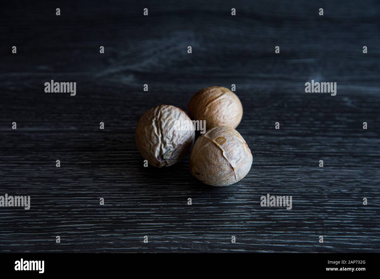 Low key image of 3 different sized avocado seeds in a group. Hard light ...