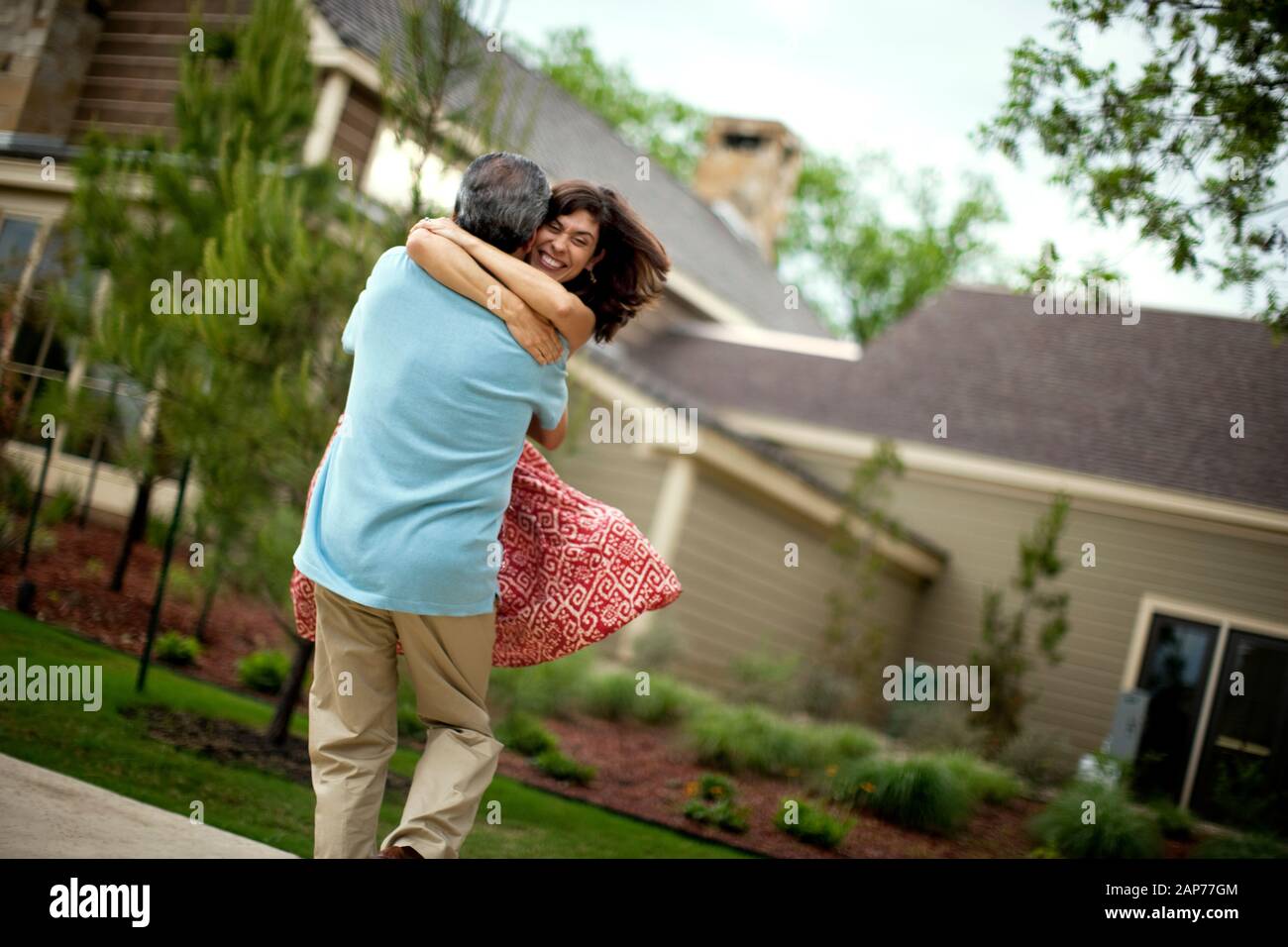 Middle-aged couple hug each other and spin around in happiness outside ...
