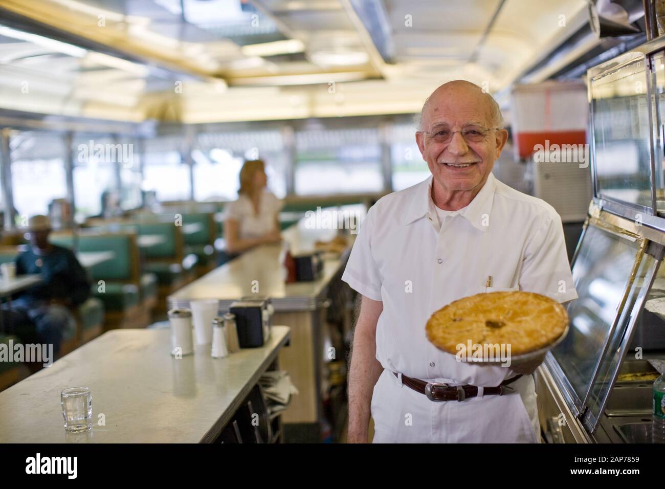 Man holding a pie behind counter in old fashioned diner Stock Photo - Alamy