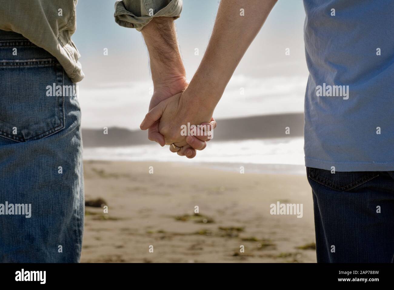 Hands of two men holding hands on a beach Stock Photo - Alamy
