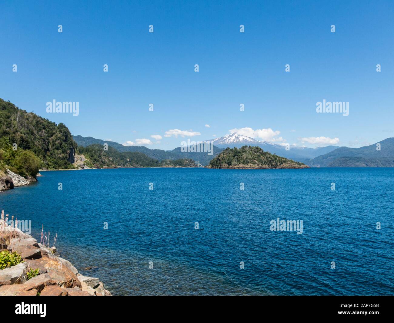 The amazing Choshuenco Volcano surrounded by clouds, above the waters ...