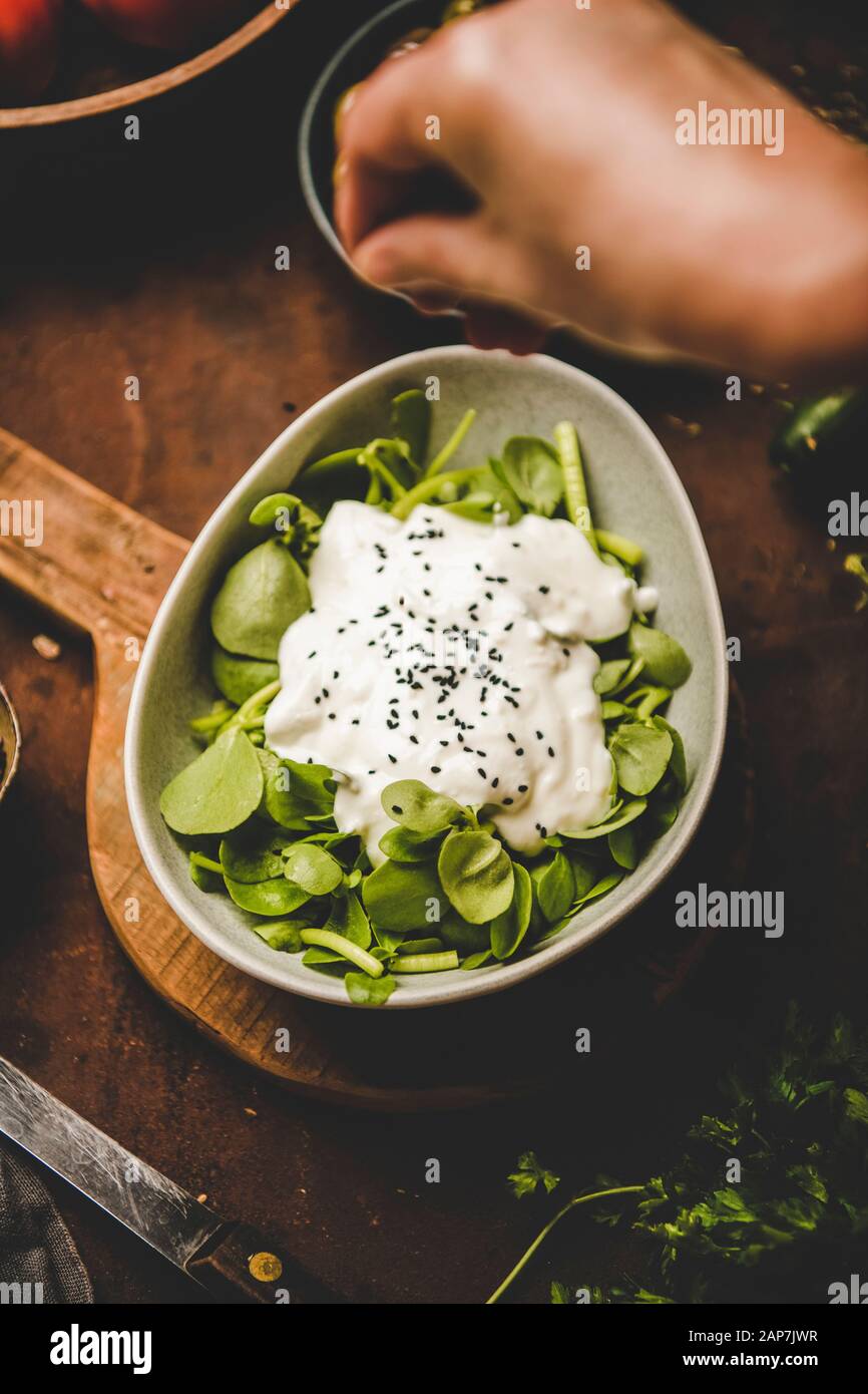 Turkish starter, meze dish. Human hand adding black sesame to bowl of ...
