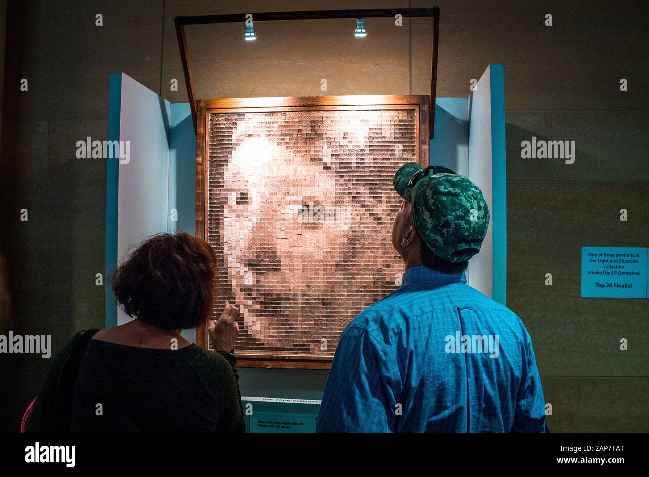 Tourists observing an portrait that is drawn using light and shadows ...