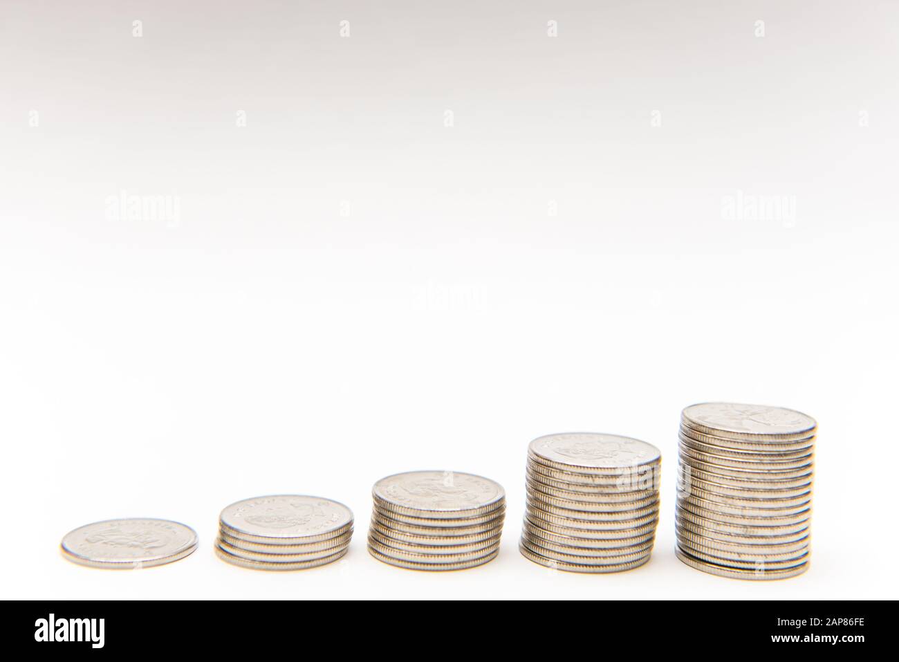 Canadian Quarters stacked into five ascending piles on white background ...