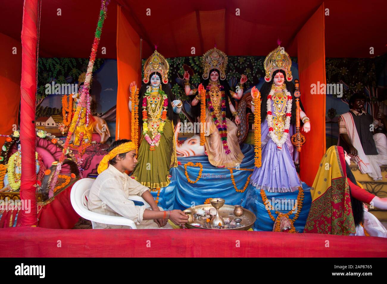 A boy collecting donations at a religious display. At the Kumbh Mela ...