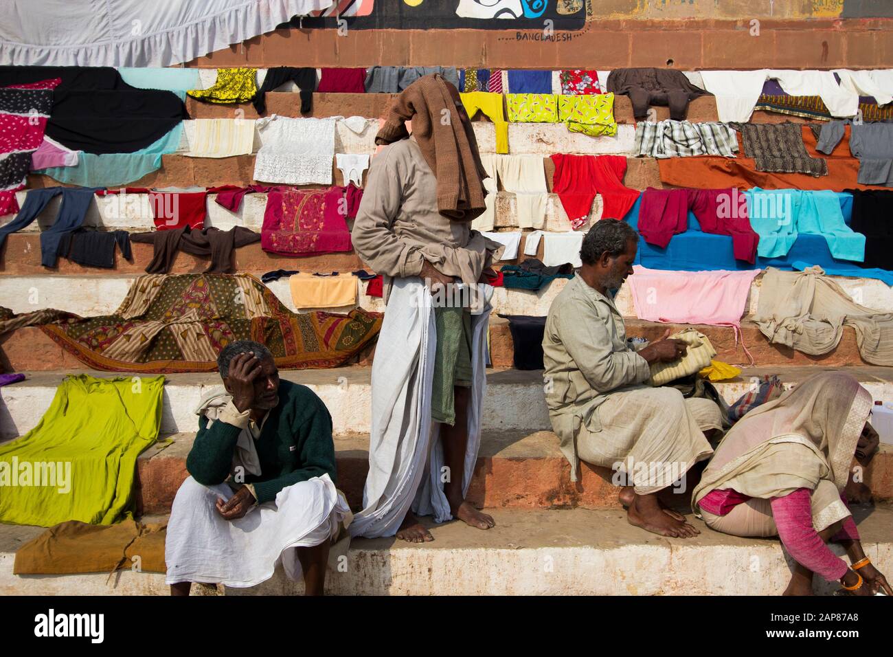 A man busy changing his clothes after bathing in the Ganges river. In ...