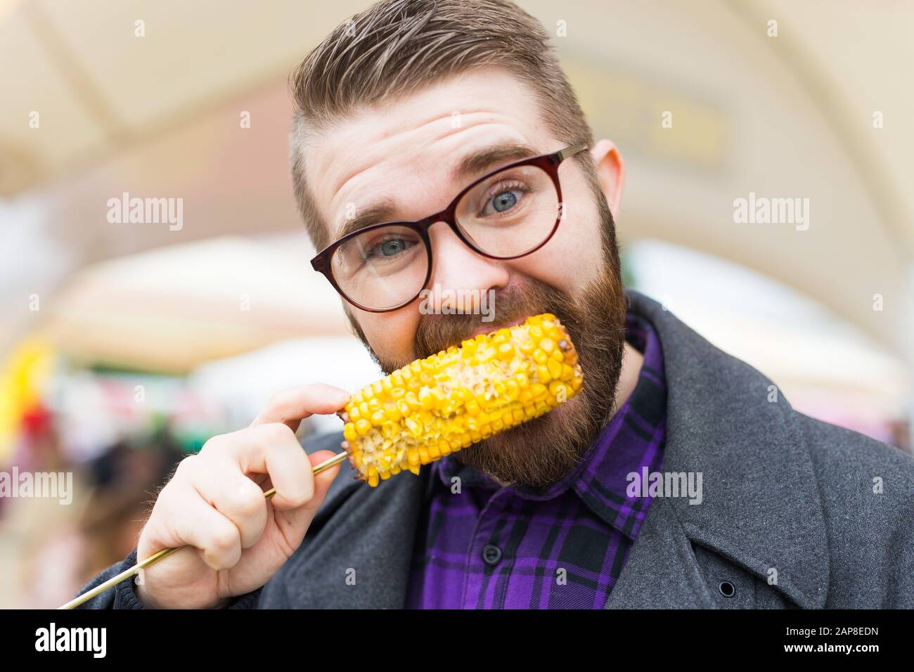 Man eating grilled corn. vegetarian food. healthy and tasty vegetables ...