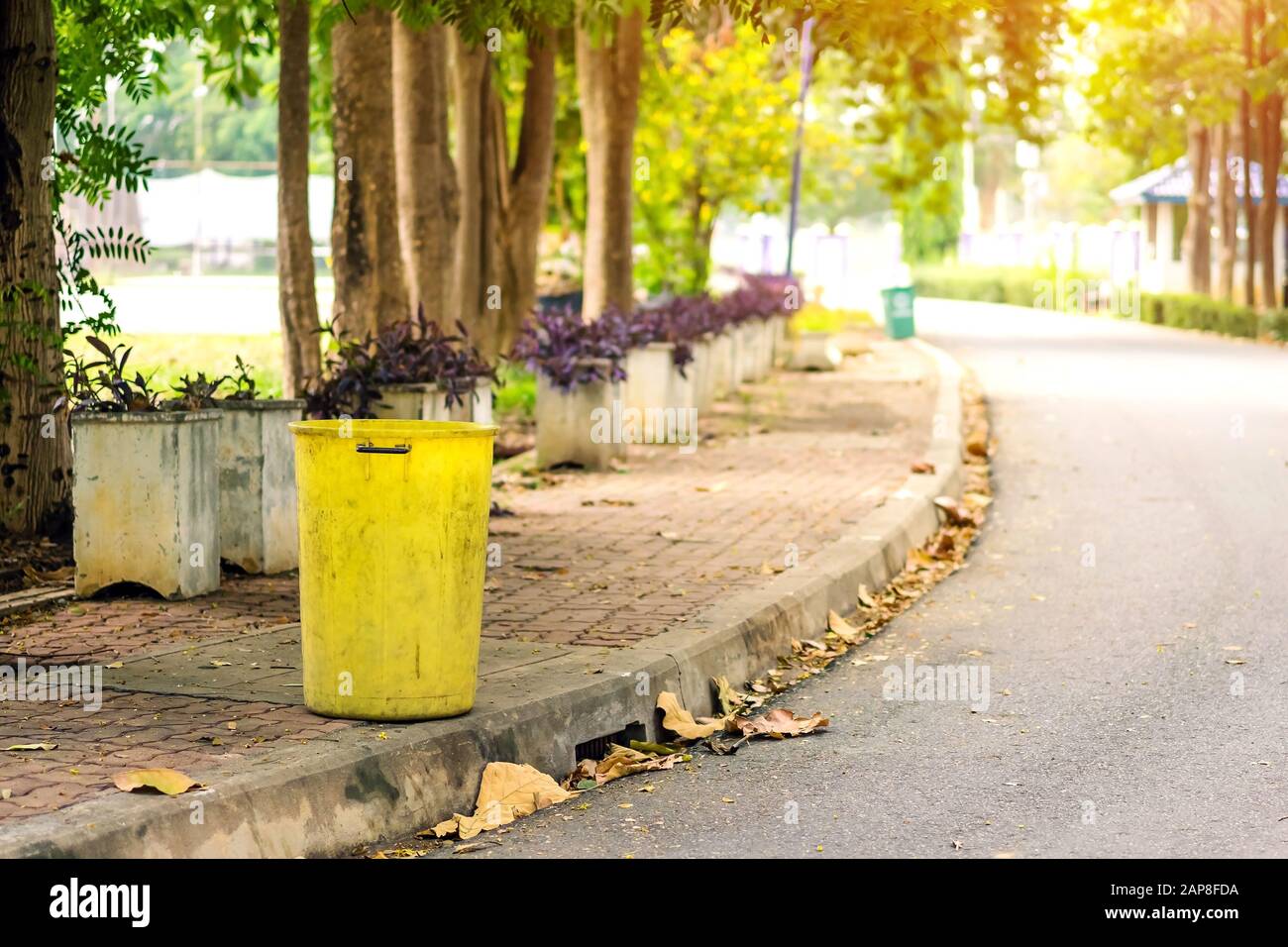 An old yellow dustbin in the public park beside the walk way for ...