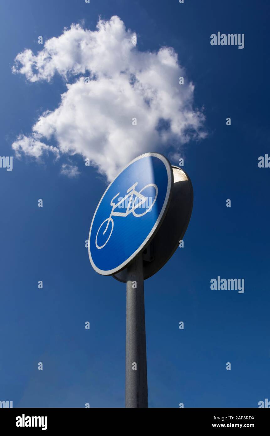 Road sign "Bike path" at an angle on a sunny day against a blue sky with a white cloud vertical ...
