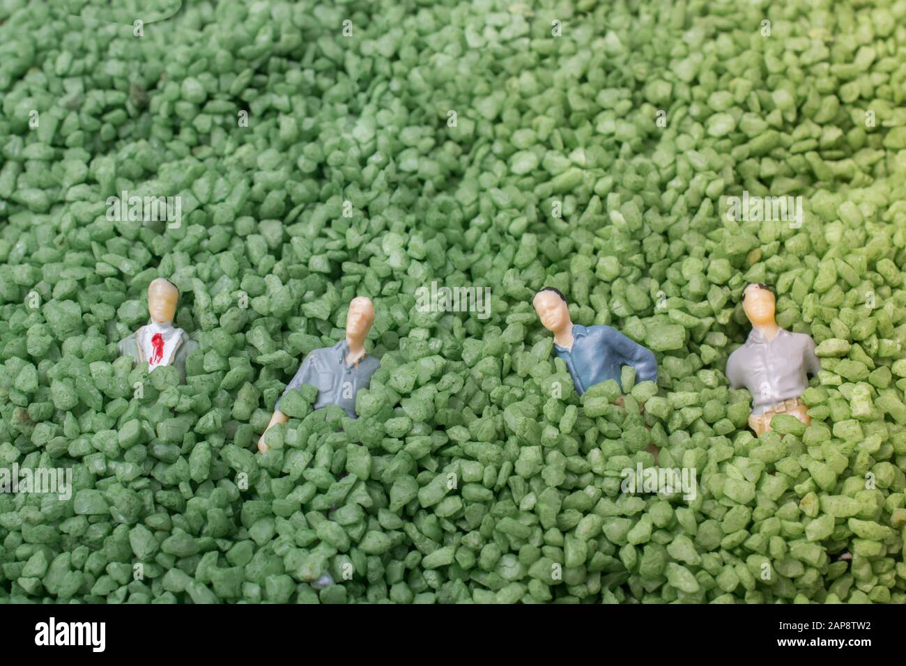 Group of tiny figurine of man in green sand Stock Photo - Alamy